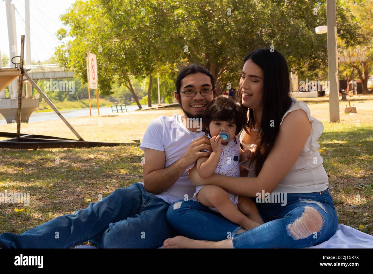 Young Hispanic parents playing with their one year old baby in a park ...