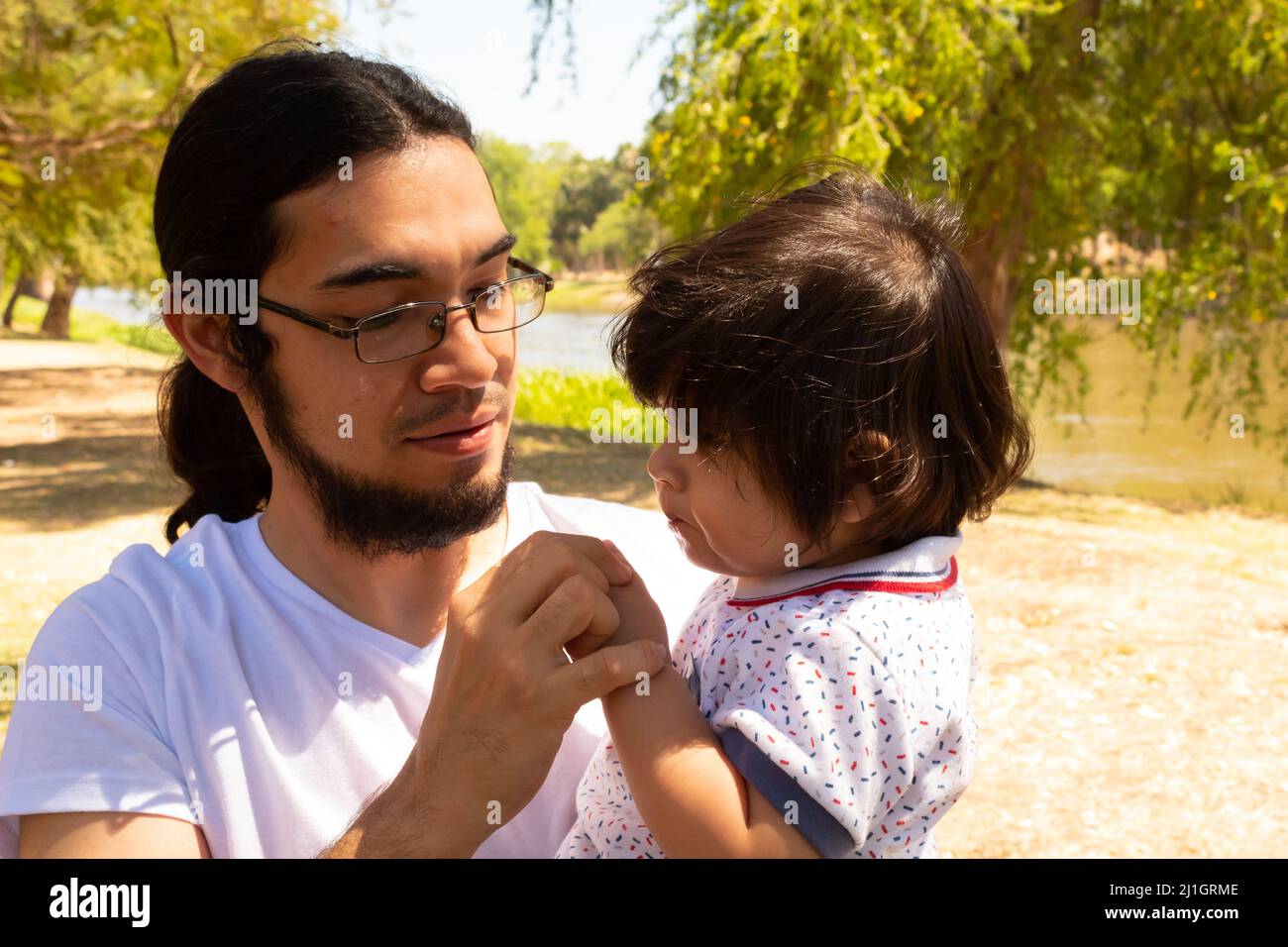 portrait of a young Hispanic father with his son in a park having fun ...