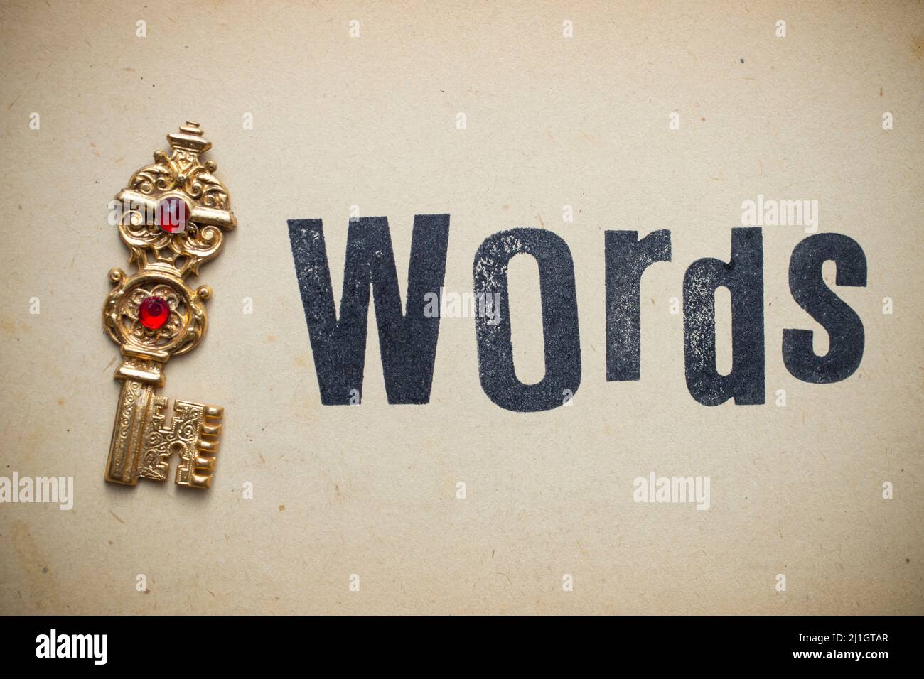Golden key next to "Words" written on yellowed vintage paper texture ...