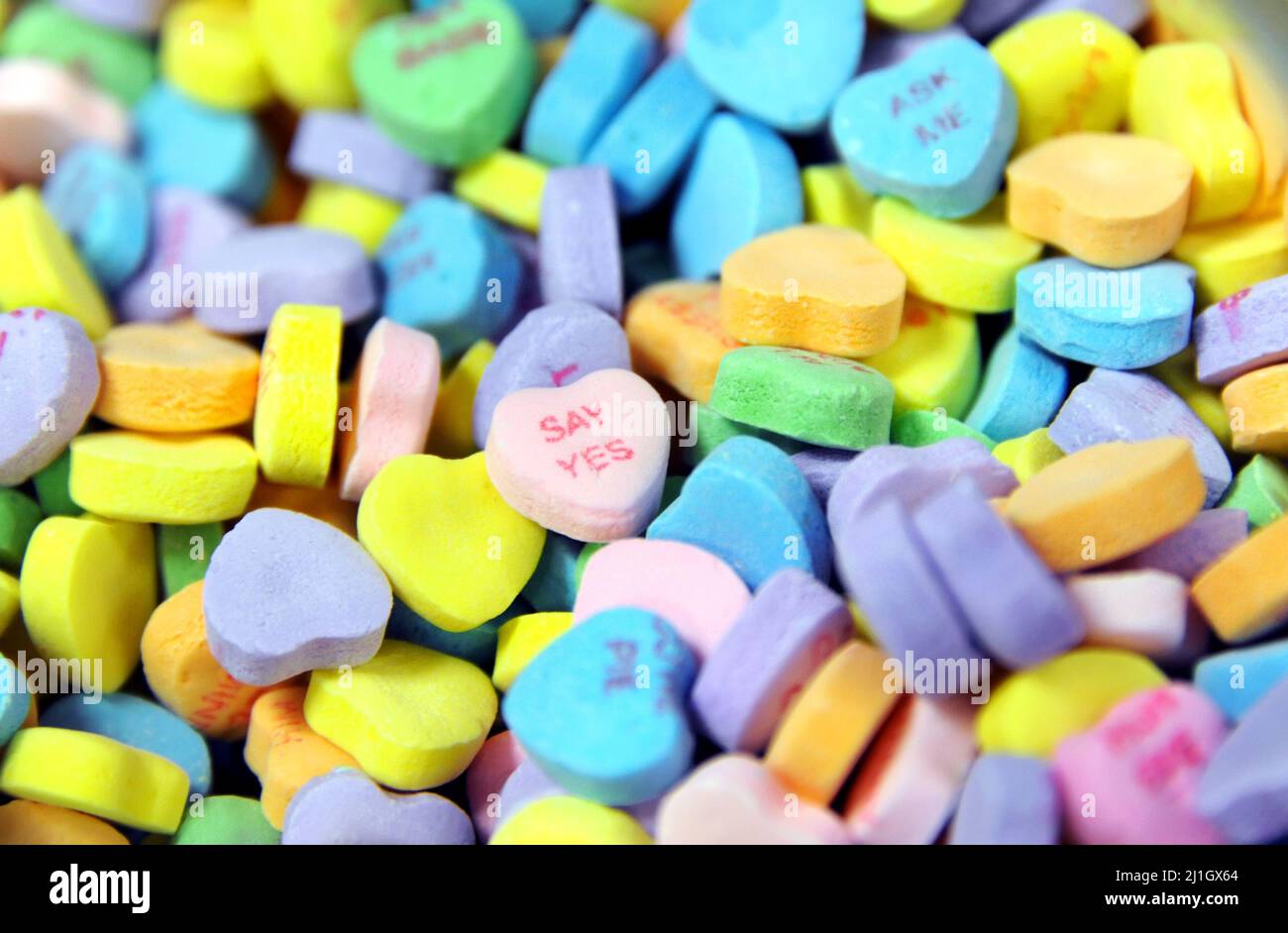 Pile of heart shaped candy sits ready for sale. Message on one heart ...