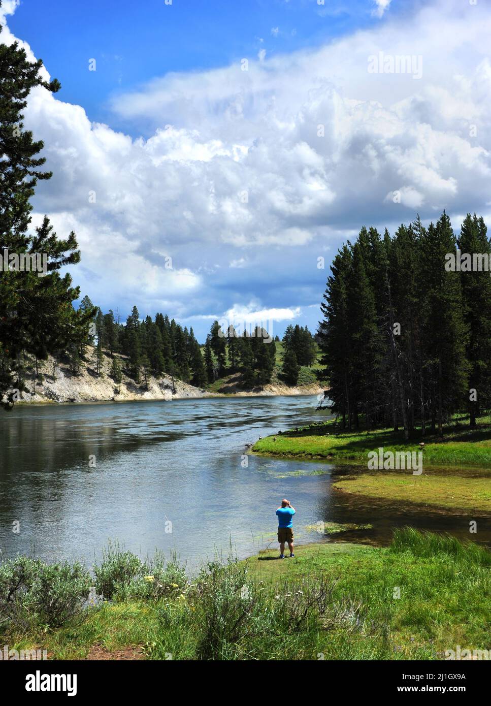 Man stands and photographs river vista in Yellowstone National Park ...