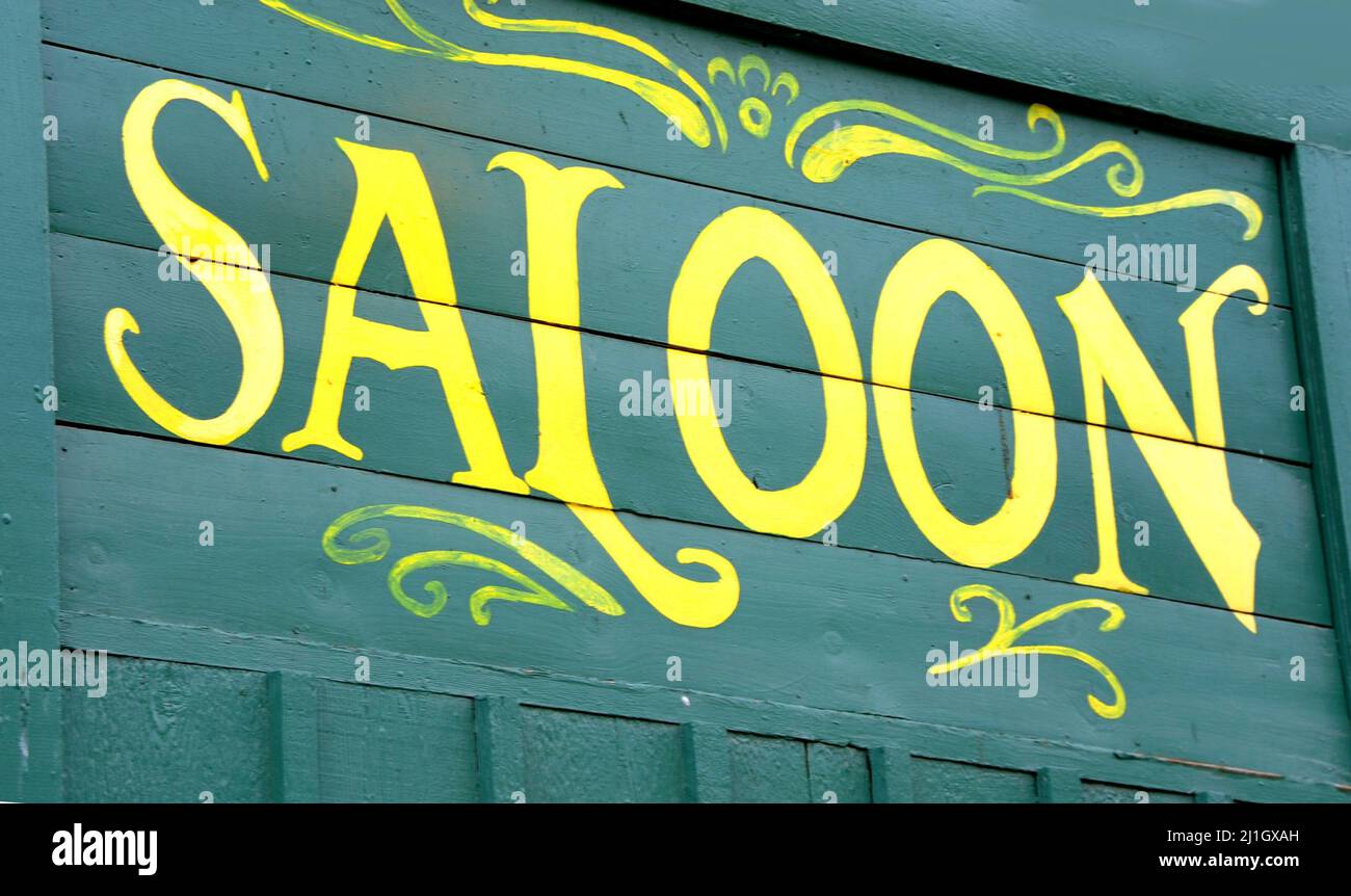 Handpainted "Saloon" sign is yellow painted on green wooden wall Stock ...
