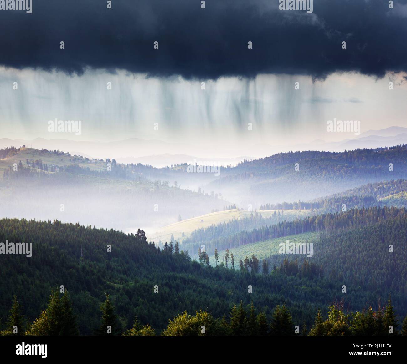 Wonderful view of the rain clouds over the wooded mountains. Dramatic ...