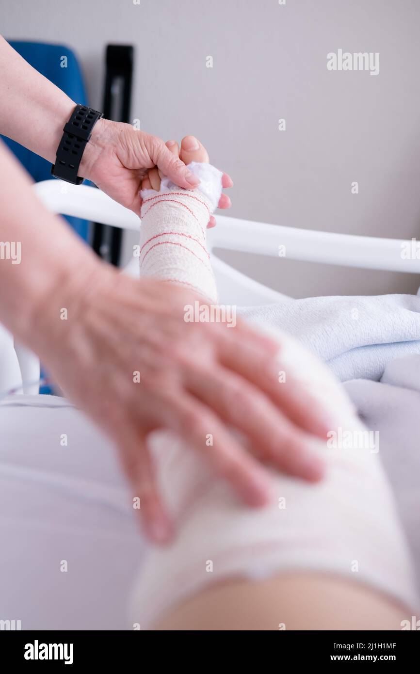 Hands of an unrecognizable person looking after an injured leg in a ...