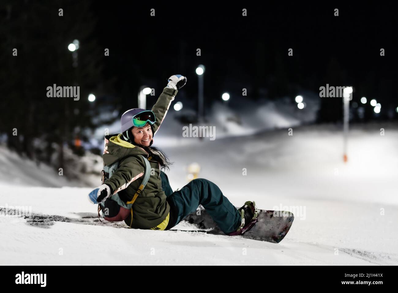 Snowboarder girl posing on slopes. Night skiing in winter resort Stock ...