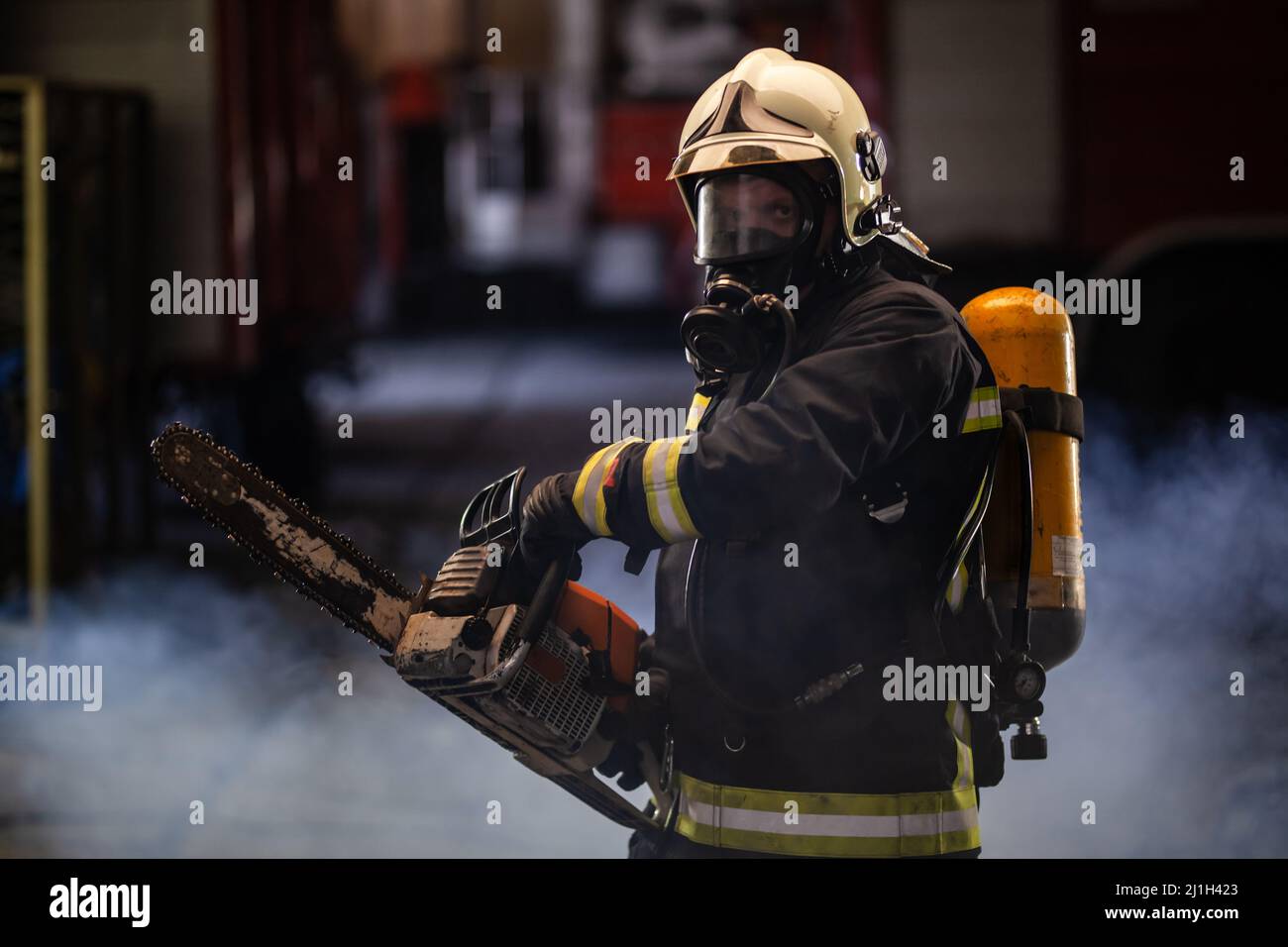 Firefighter portrait wearing full equipment, oxygen mask, and chain saw ...