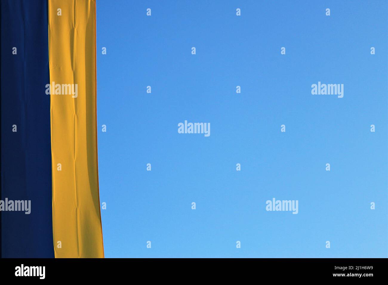 Flag of Ukraine as a banner flying vertically against a clear blue sky ...