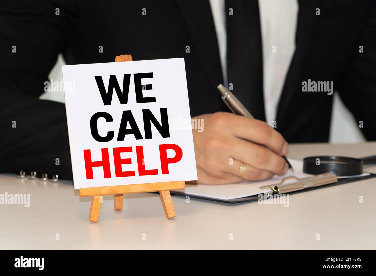 Paper note pinned to a cork notice board with the phrase We Can Help ...