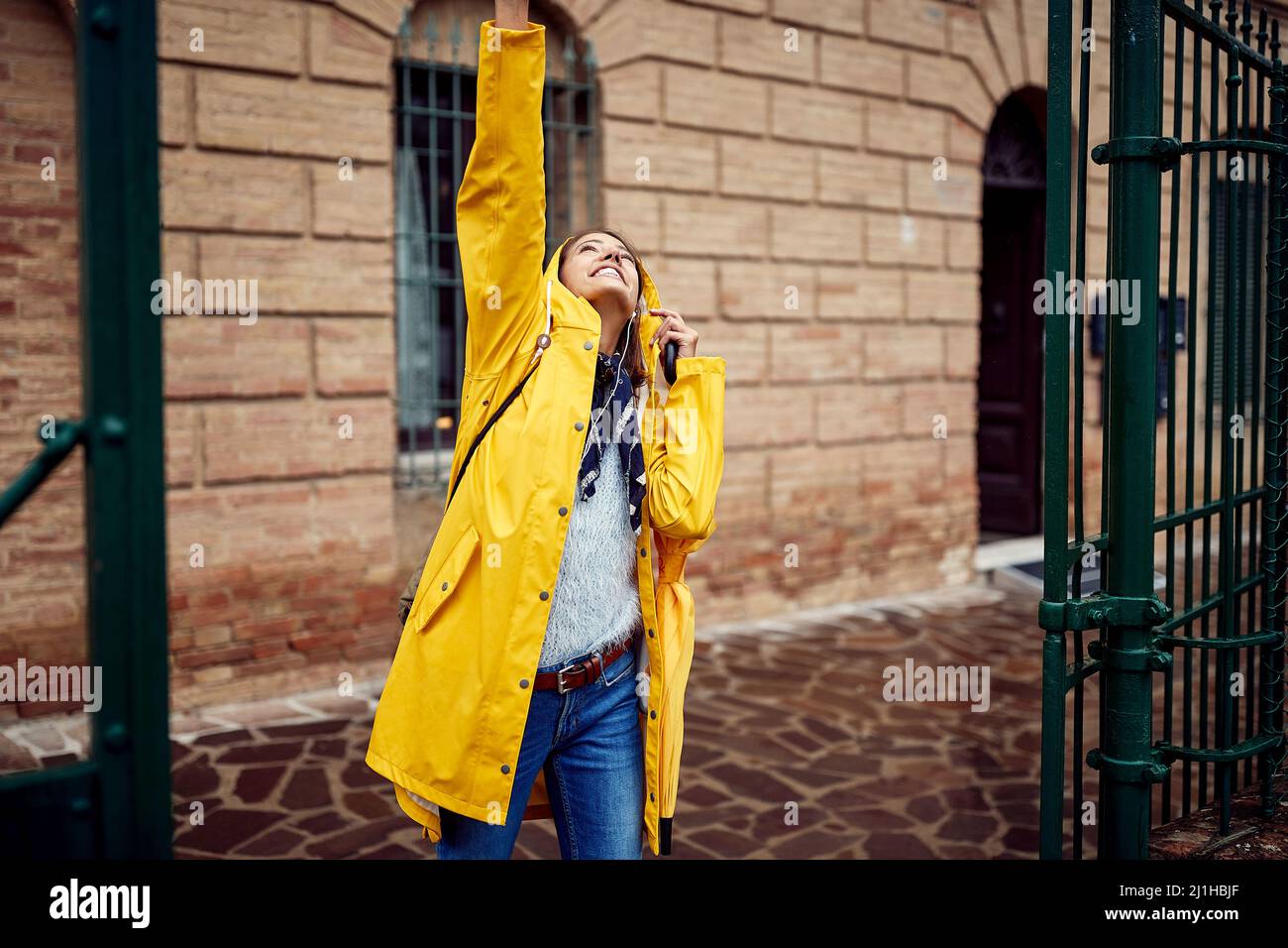 A young girl is excited about rain drops falling on her on a rainy day ...