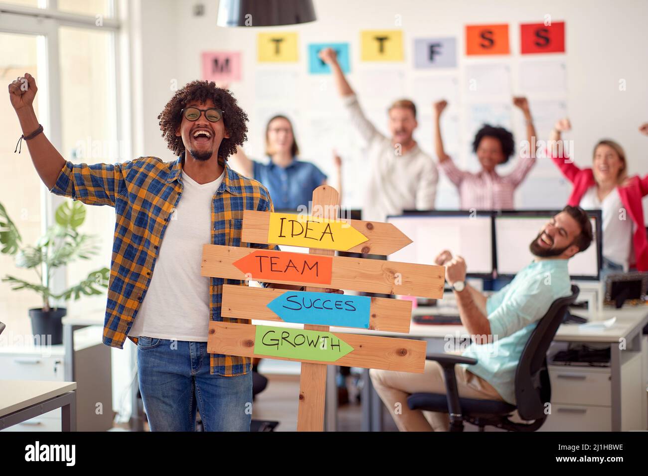 A young cheerful male office worker is holding a sign with company ...