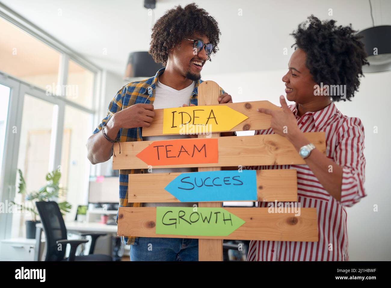 Young cheerful colleagues are enjoying to promote company slogans and ...