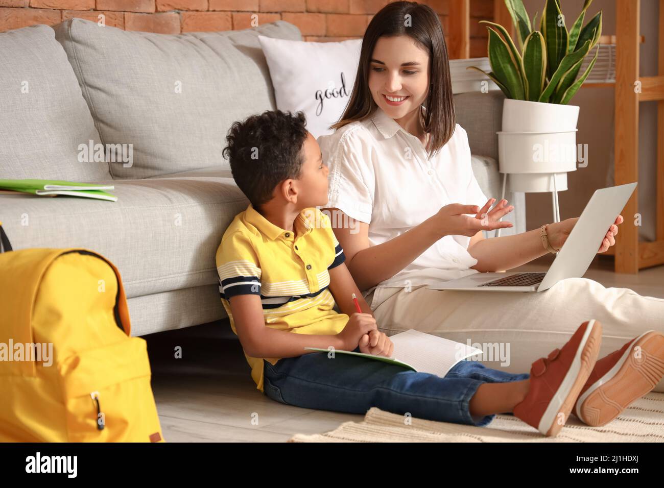 Little African-American boy studying with tutor and laptop at home ...