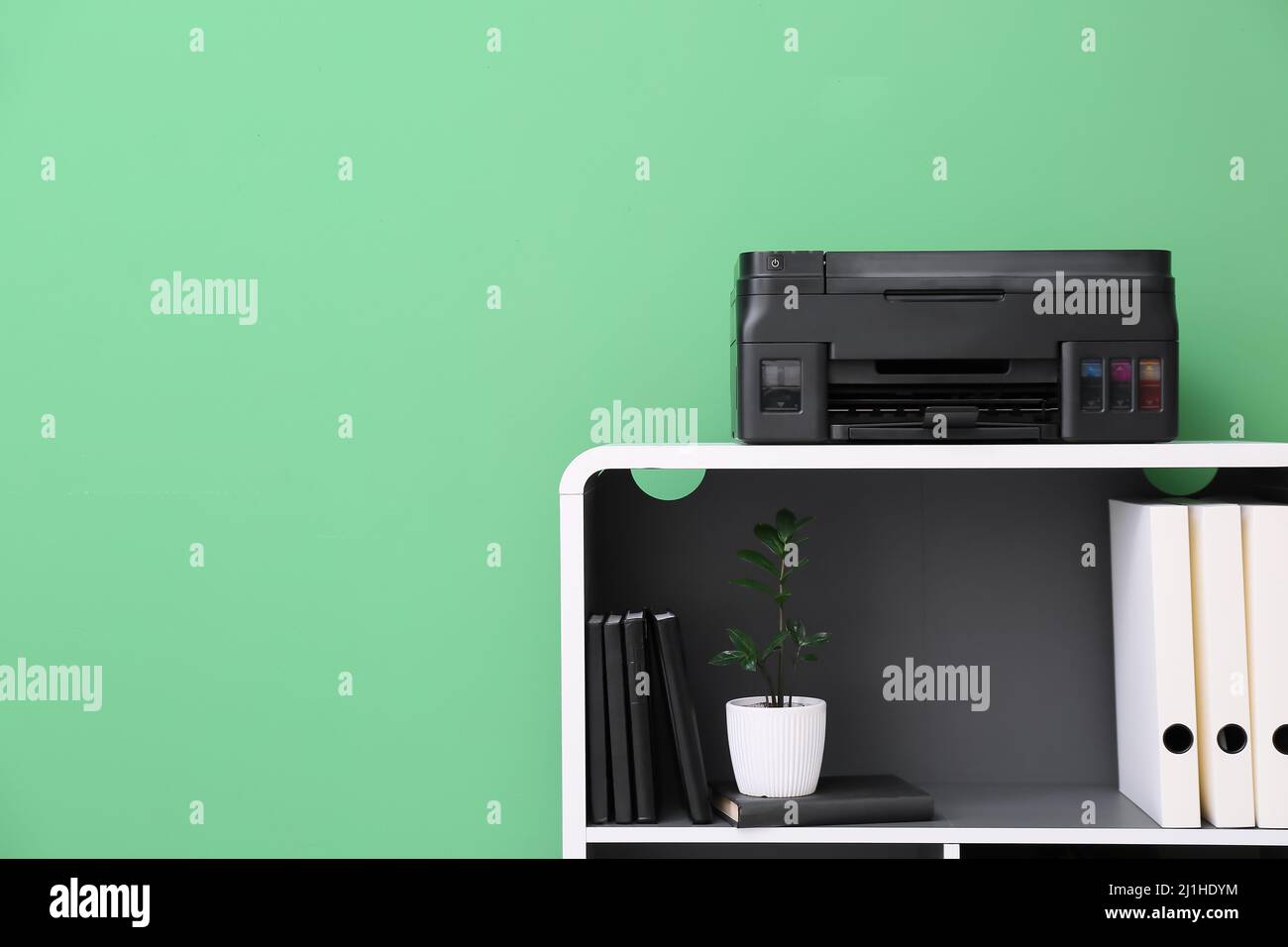Shelf unit with modern printer near green wall Stock Photo - Alamy