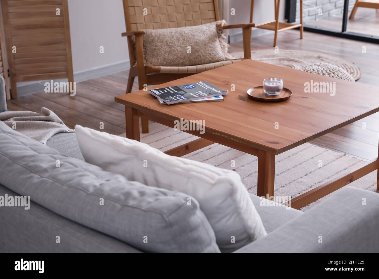Modern table with candle, magazine and sofa in interior of room Stock ...