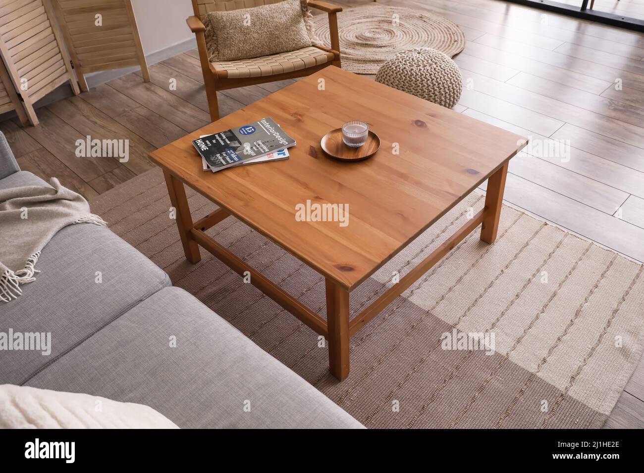 Modern table with candle, magazine and sofa in interior of room Stock ...