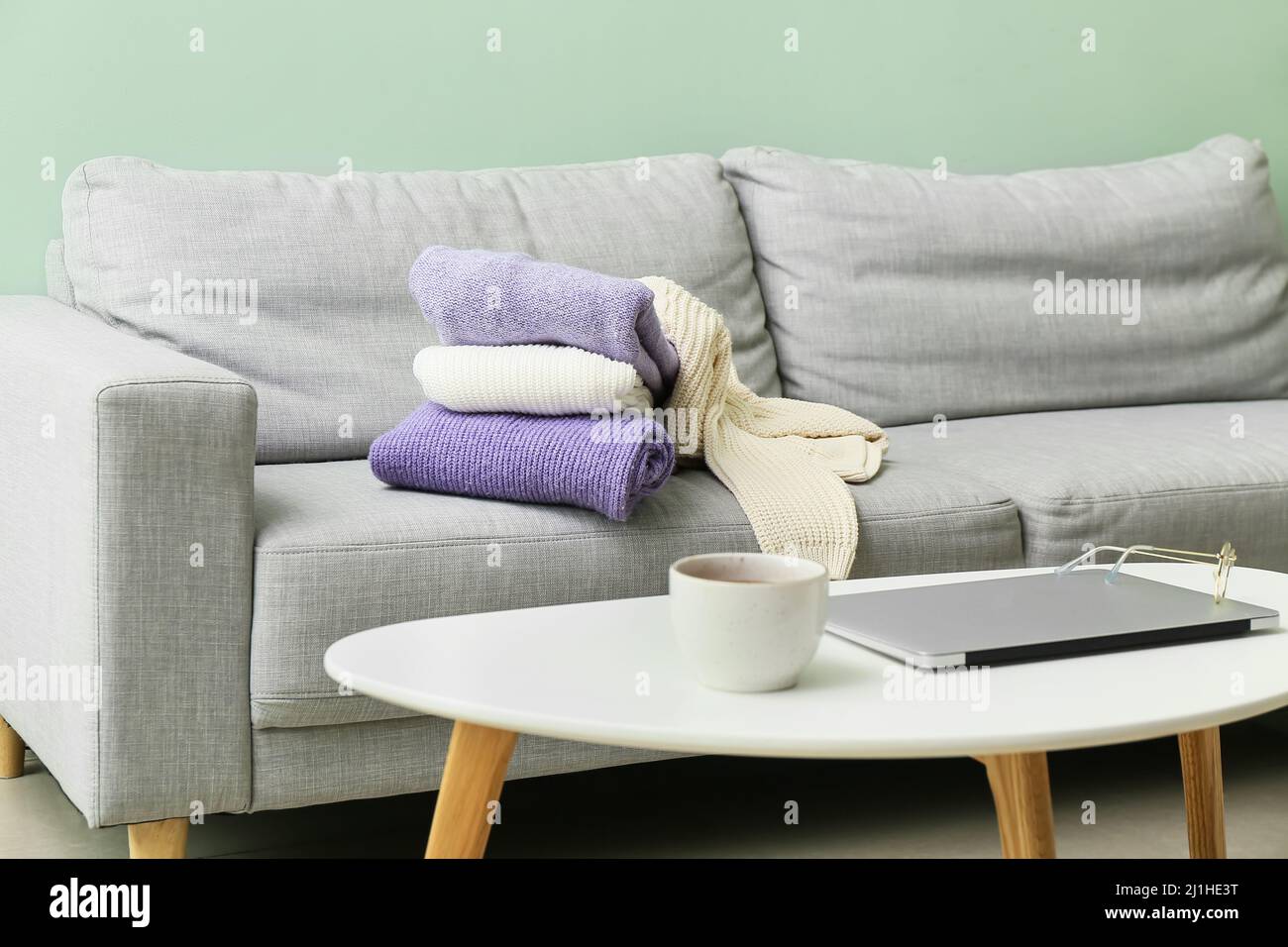 Stack of knitted sweaters on sofa in room Stock Photo - Alamy