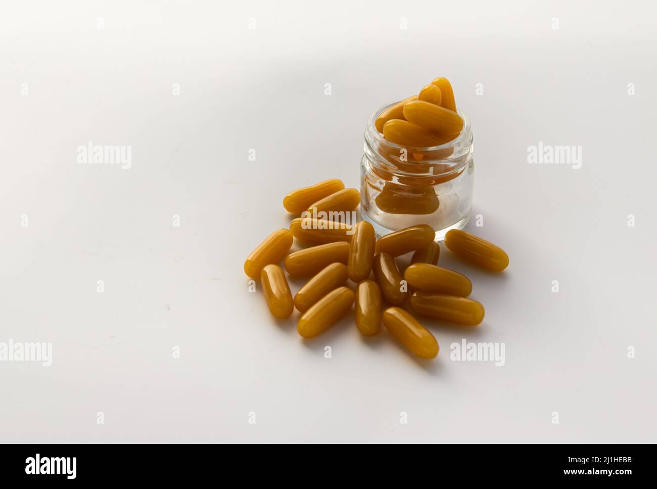 Golden oil capsules in glass bottle on white background. Nutritional ...