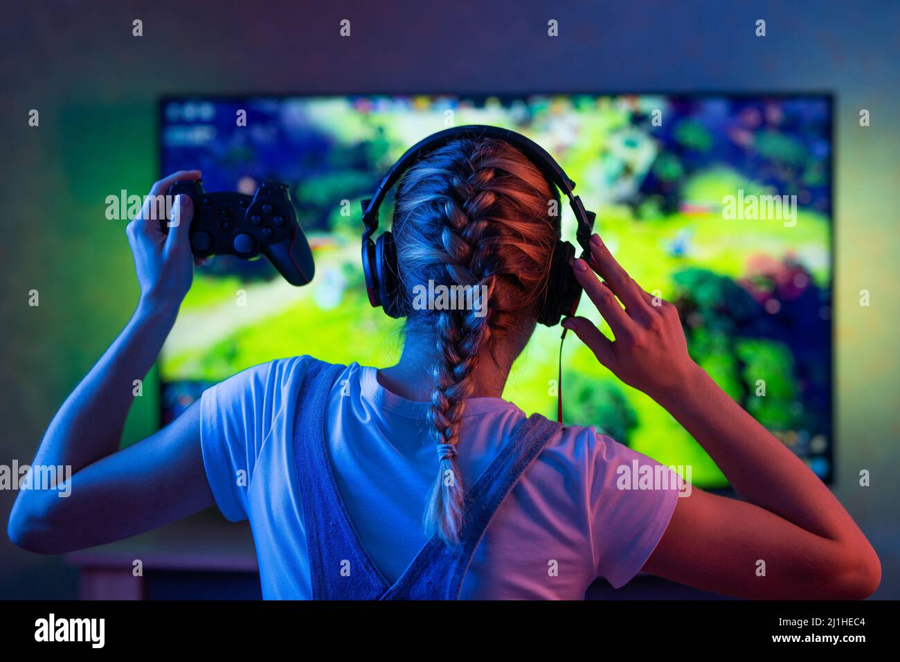 A gamer or a streamer girl at home in a dark room with a gamepad ...