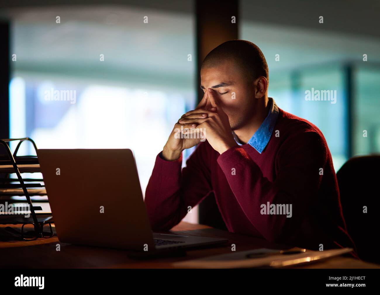 The deadline is looming. Shot of a young man looking stressed out while ...