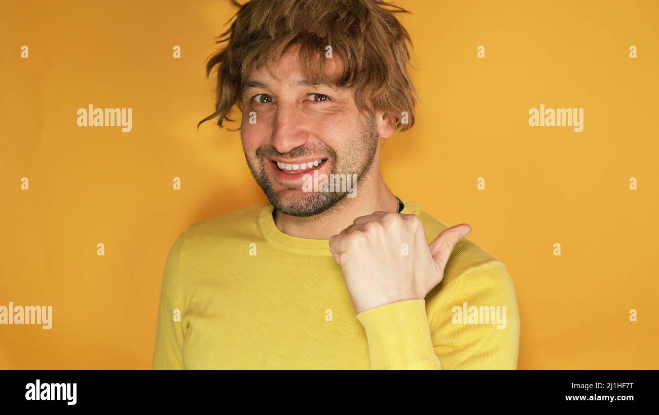 Young man wearing a yellow shirt standing over isolated yellow ...