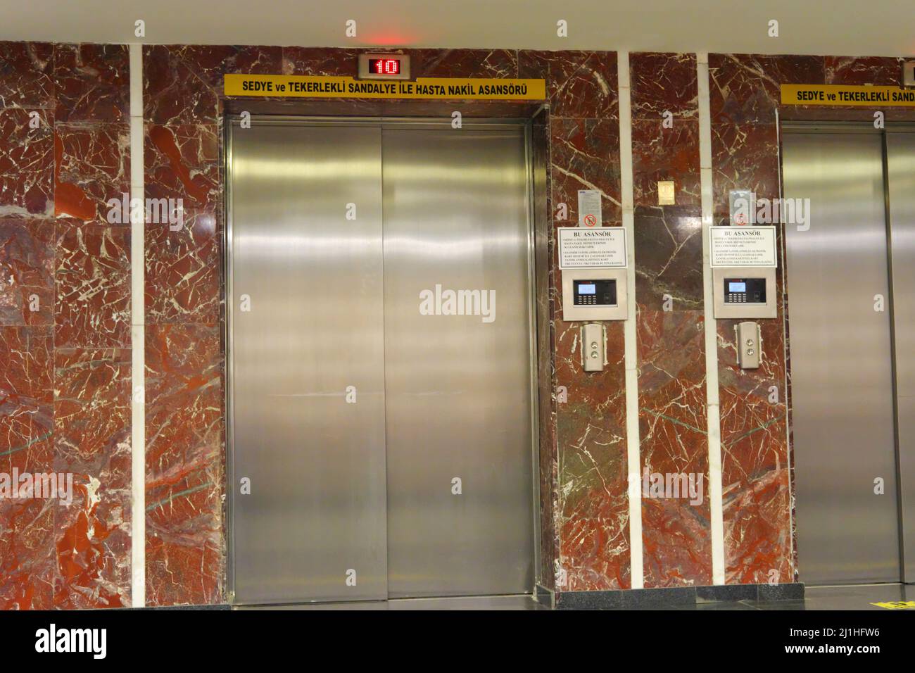 Metal door of hospital elevator with digital panel and marble wall ...