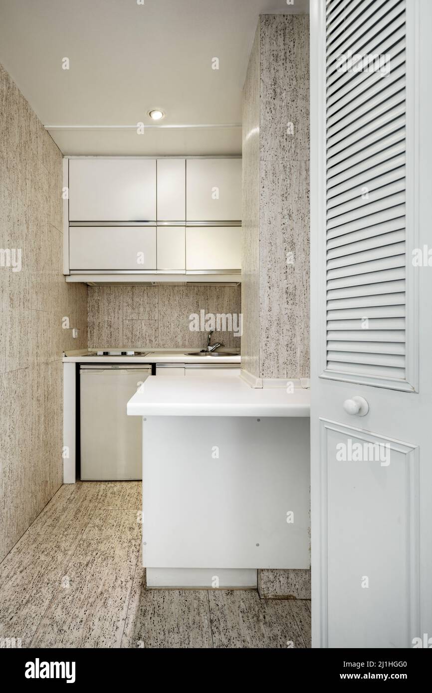 Small kitchen with white wooden furniture in a cubicle with marble ...