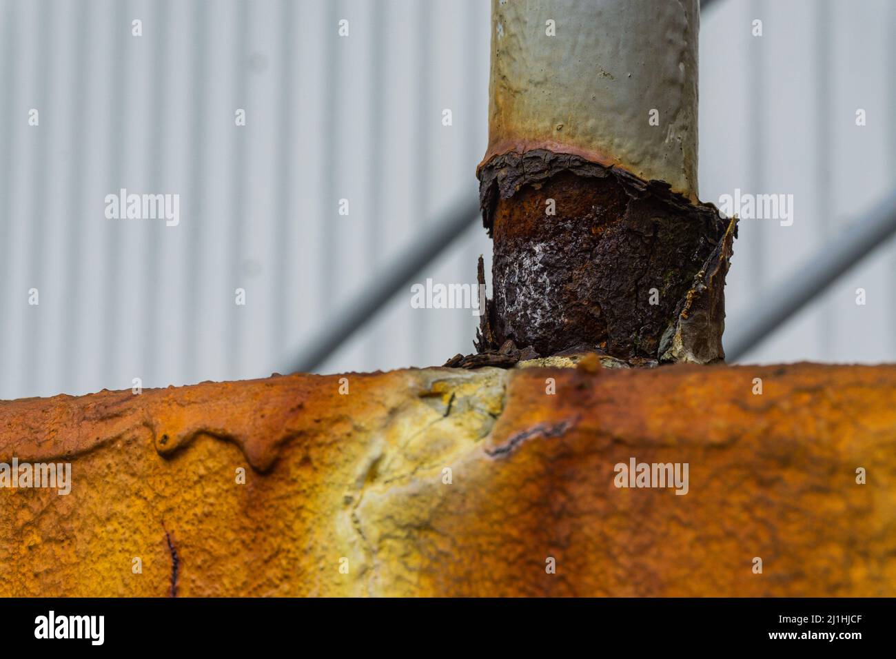 Decaying rusted pole at the base of safety railing on top of rust ...