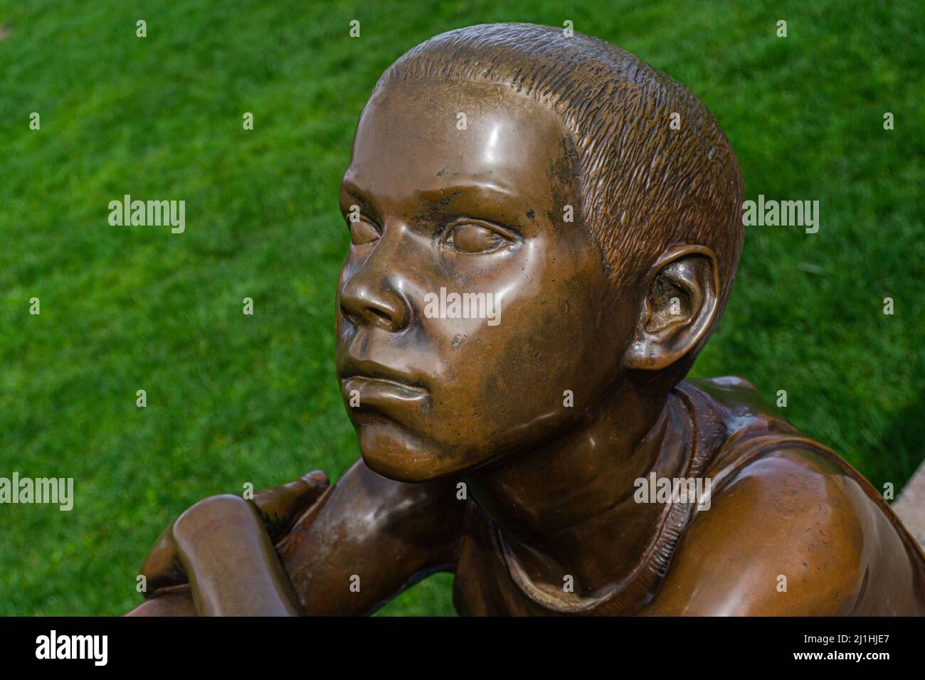Child statue looking upward in front of green grass background Stock ...