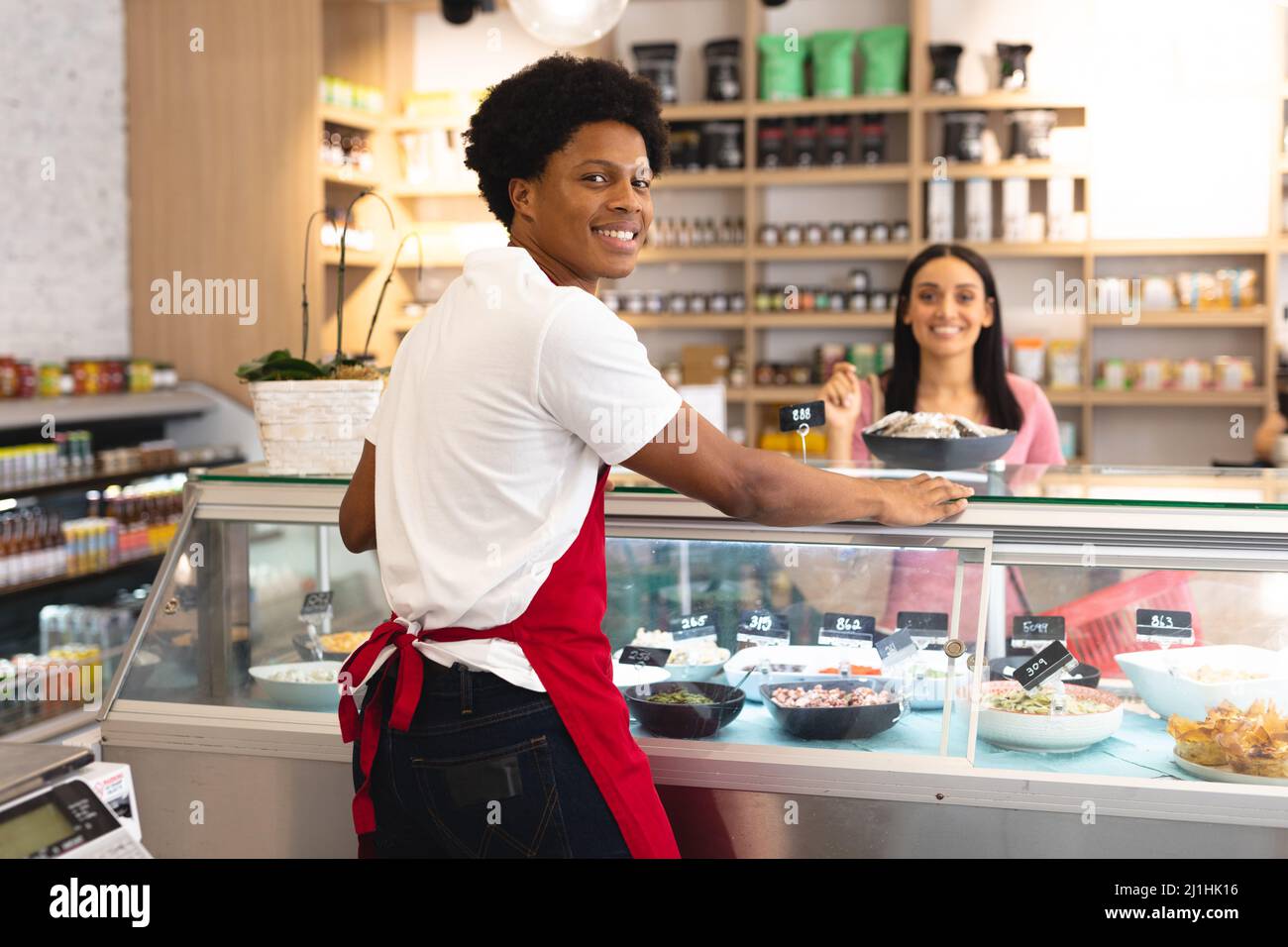 Portrait of smiling multiracial owner and customer standing by cabinet ...
