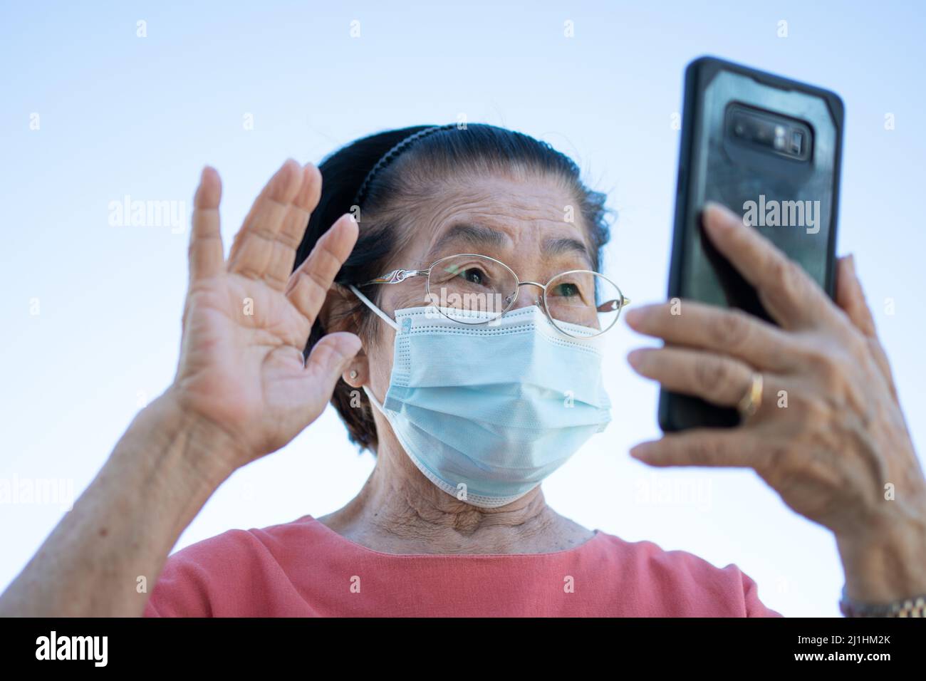 Happy Asian elderly wearing a face mask and answering a Video Call ...
