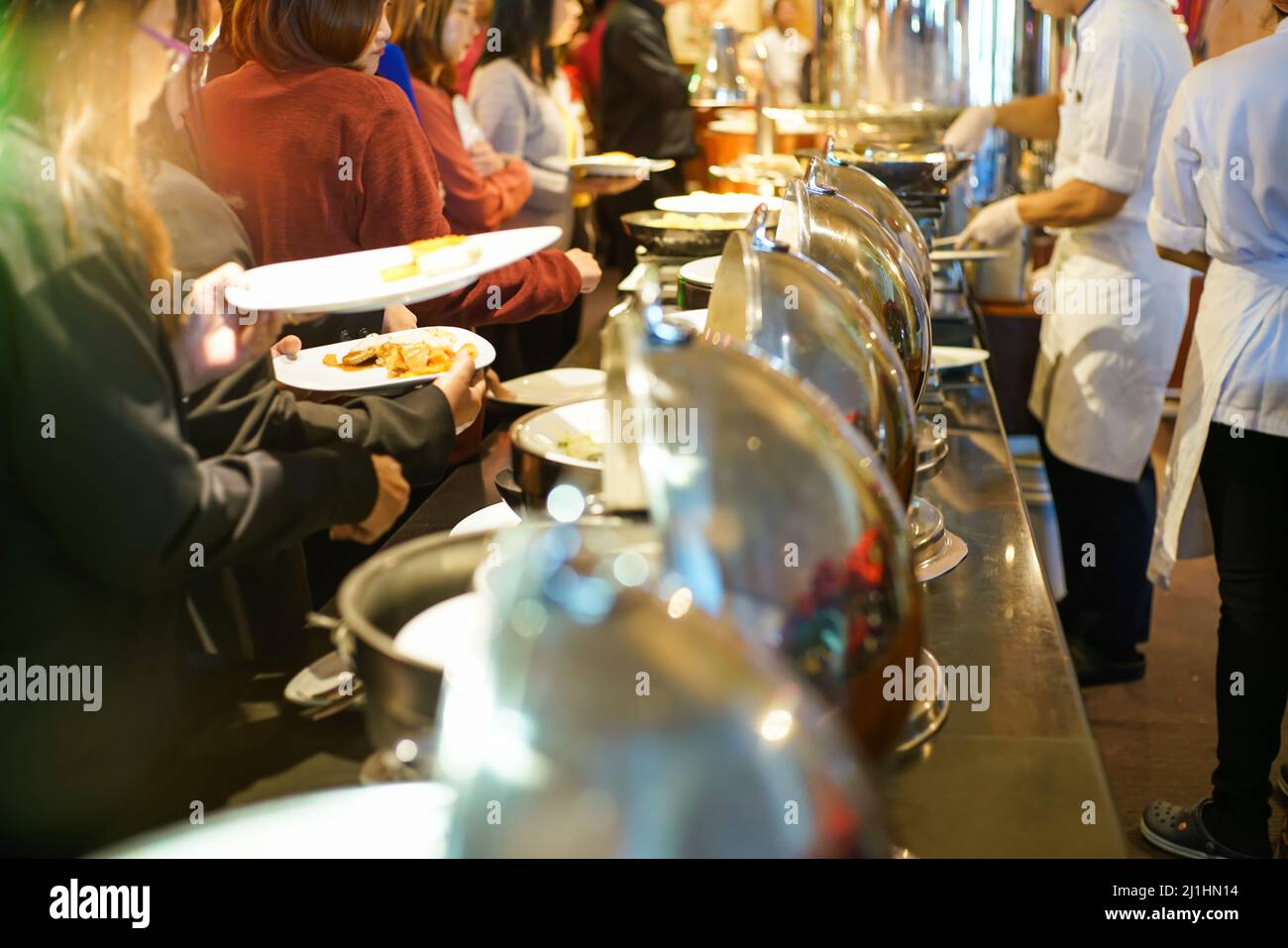 Group of people grab some buffet self service food on their own plate ...