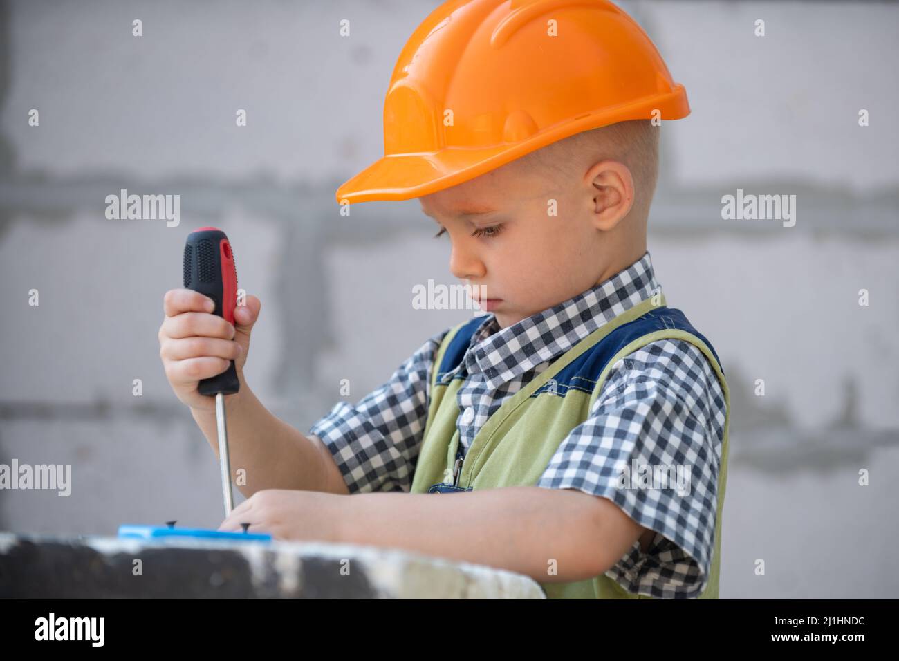 Kid boy twists bolt with screwdriver. Child repairman with repair tool ...