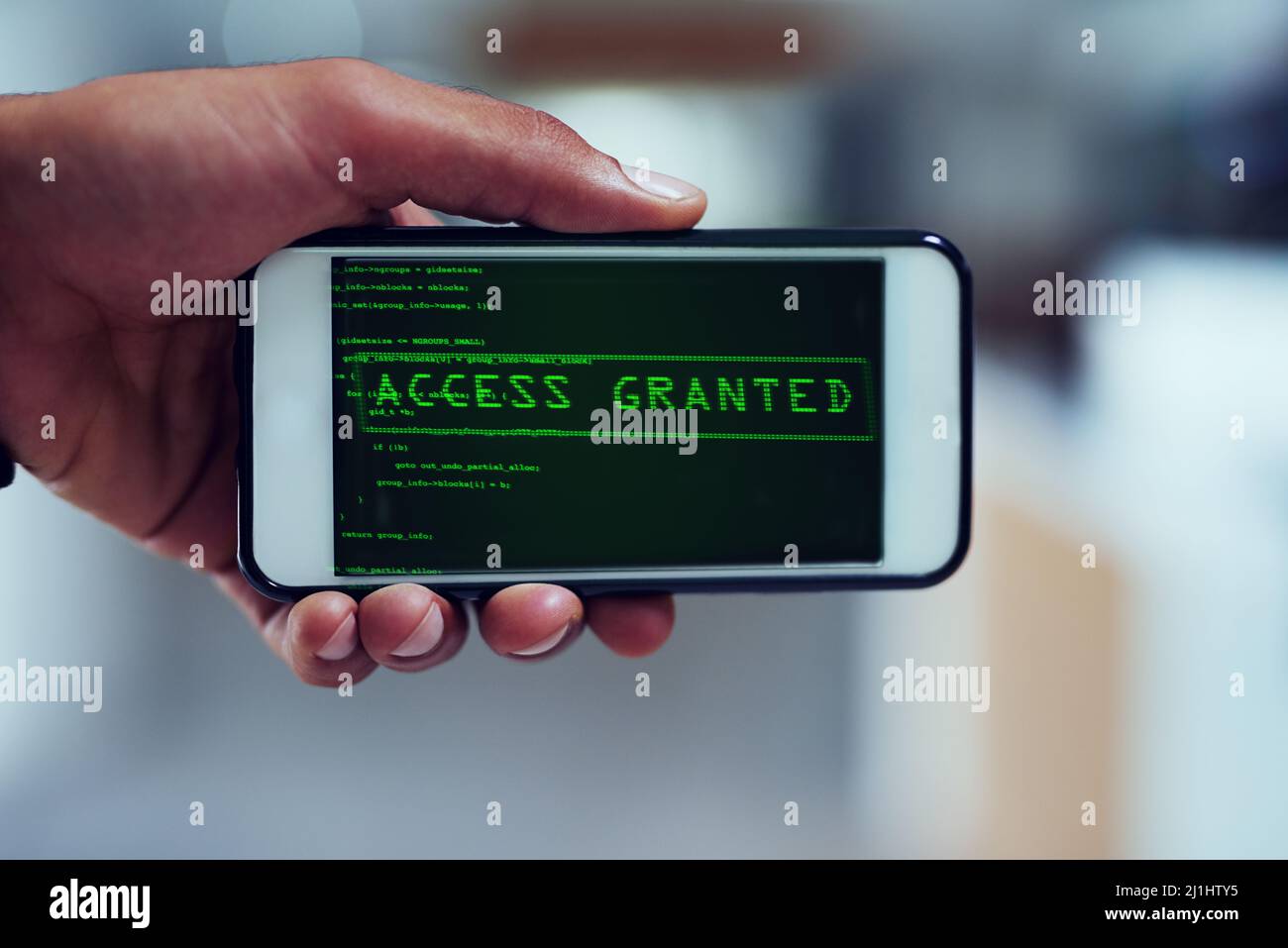 Not even your smartphone is safe. Shot of an unidentifiable man using a smartphone to hack into ...