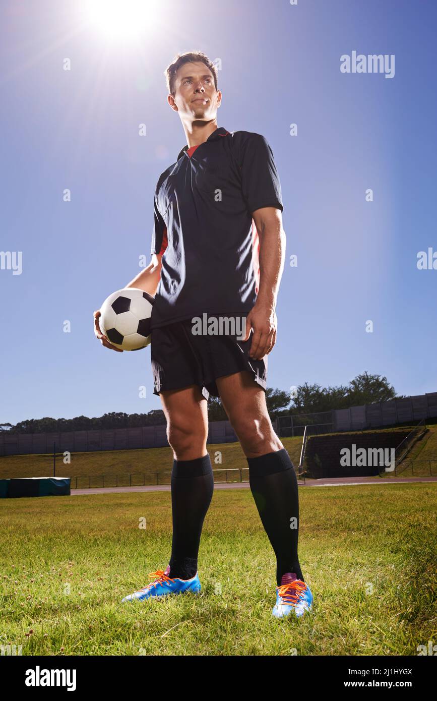 The games hero. Shot of a young footballer standing on a field with a ...
