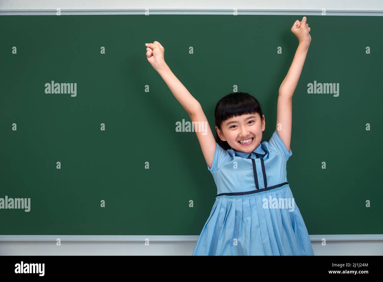 Primary school girl standing in front of the blackboard Stock Photo - Alamy
