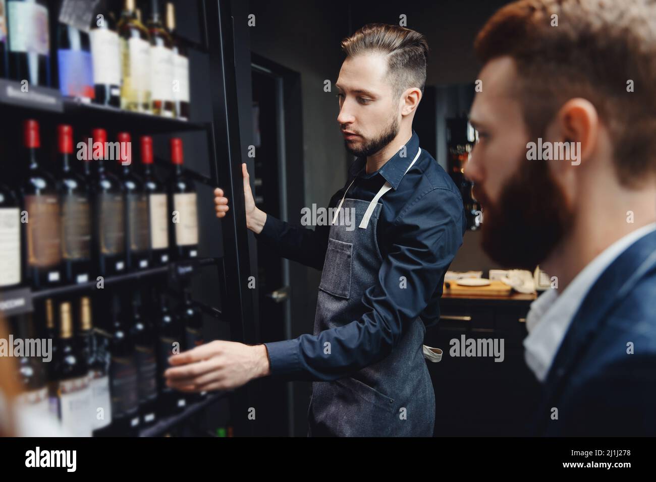 Man sommelier helps visitors to restaurant or liquor store to choose ...