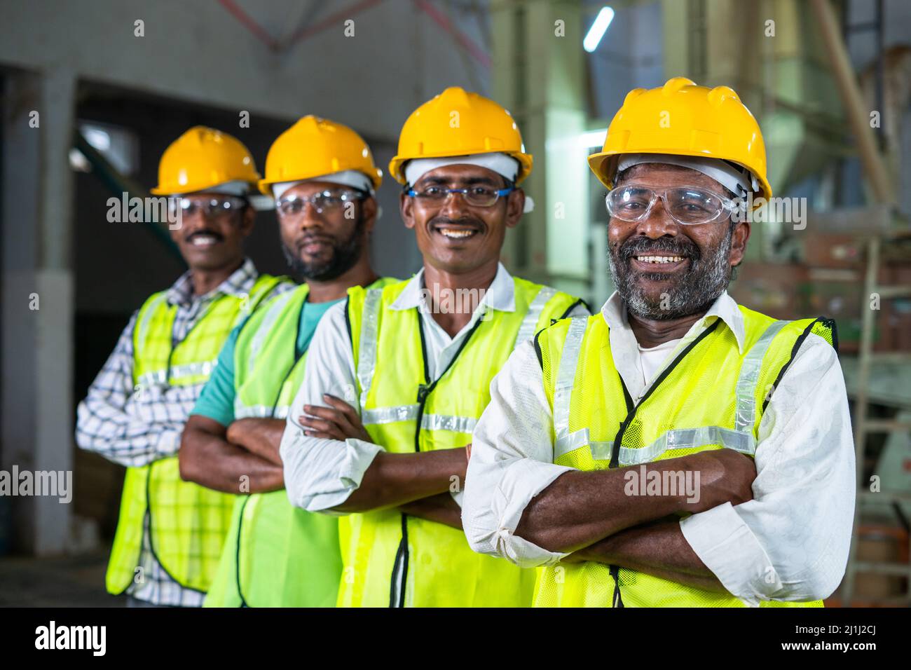 Confidently standing industrial workers with arms crossed by looking at ...