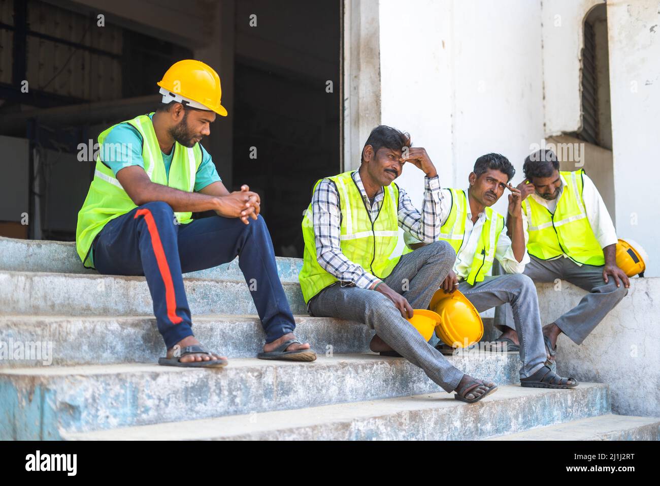 Worried Industrial Workers Sitting Outside The Factory Due To Closure