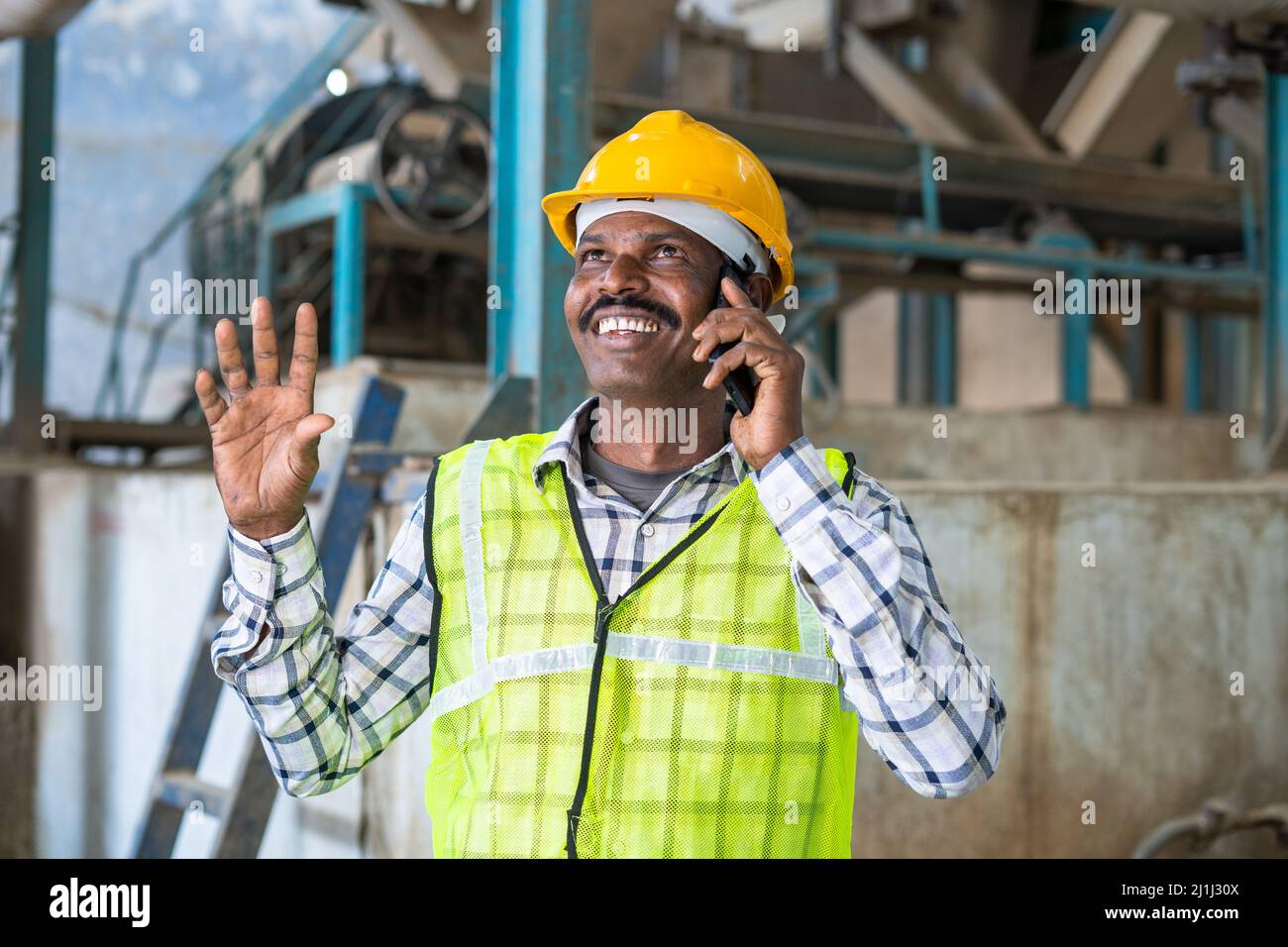 smiling industrial worker talking on mobile phone with family at ...