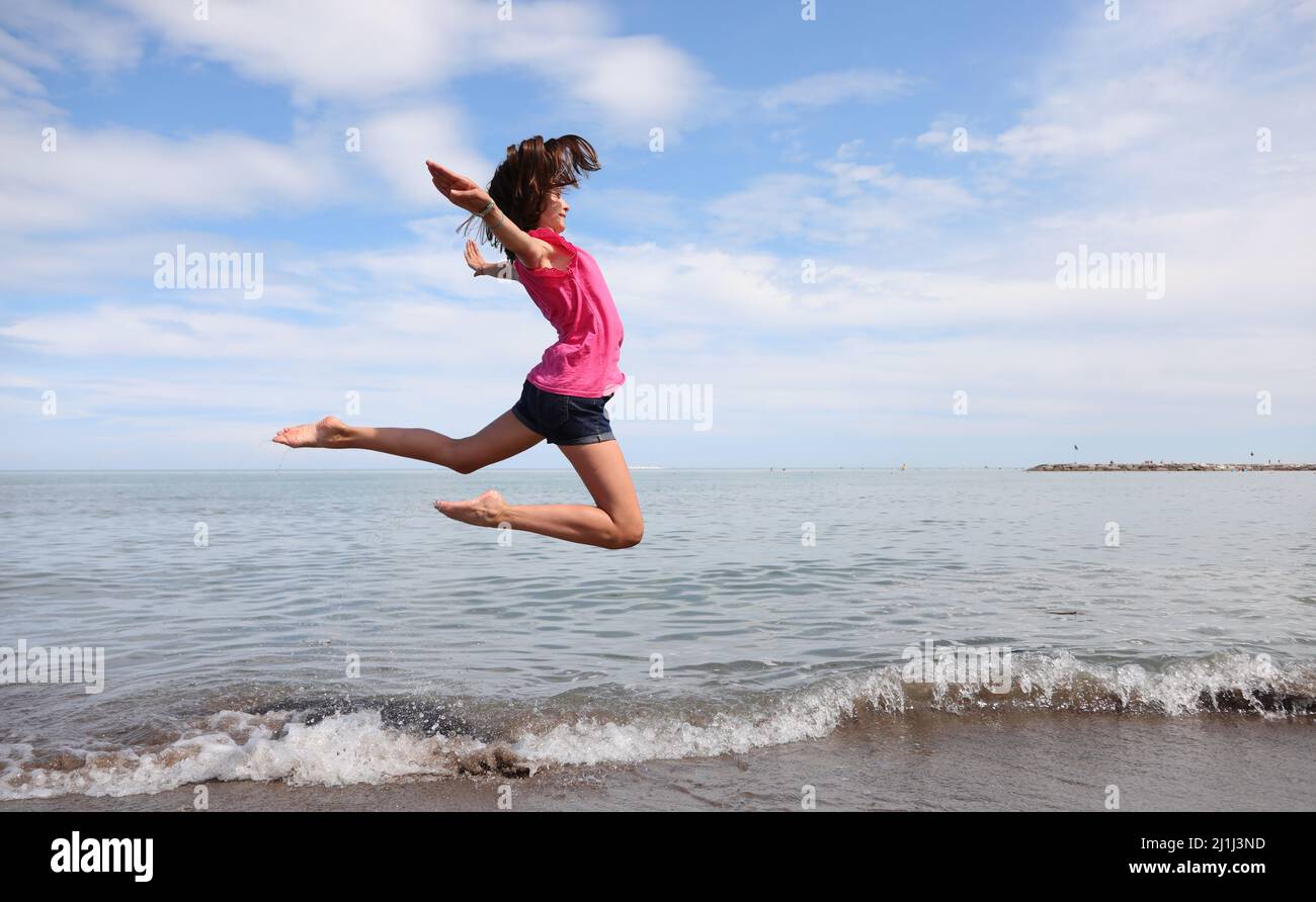 athletic girl by the sea performs rhythmic gymnastics exercises making ...