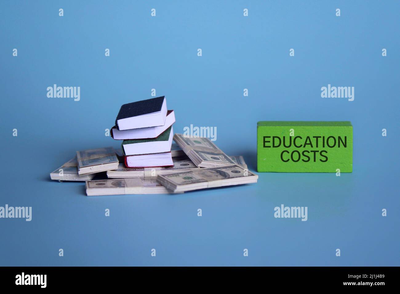 Stack of books on top of banknotes and wooden cube with text EDUCATION ...