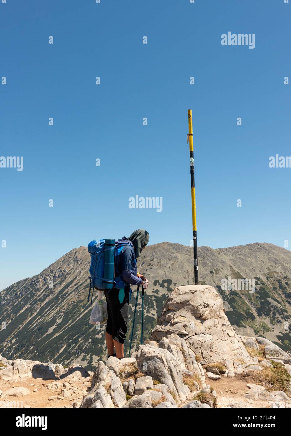 Lone backpacker at winter hiking route marker on sunny summer day and ...