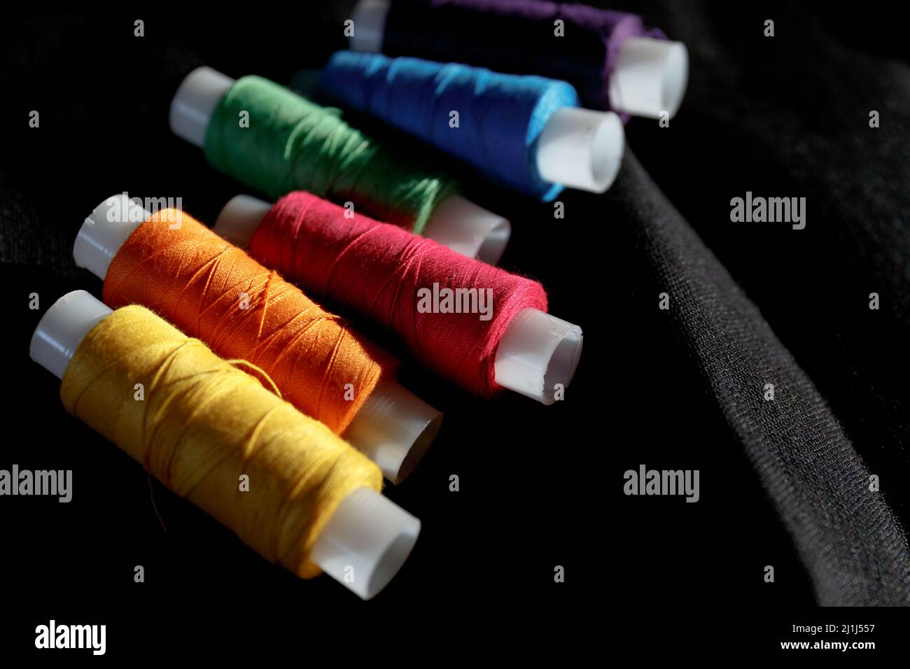 Bobbins of multicolored thread. A set of sewing thread reels on black ...