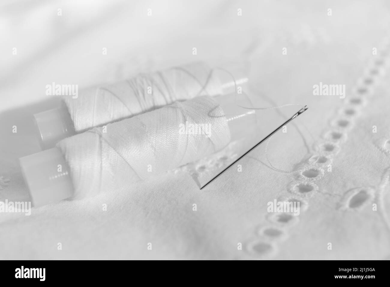 White threads. Two spools of white cotton thread on a smooth fabric ...