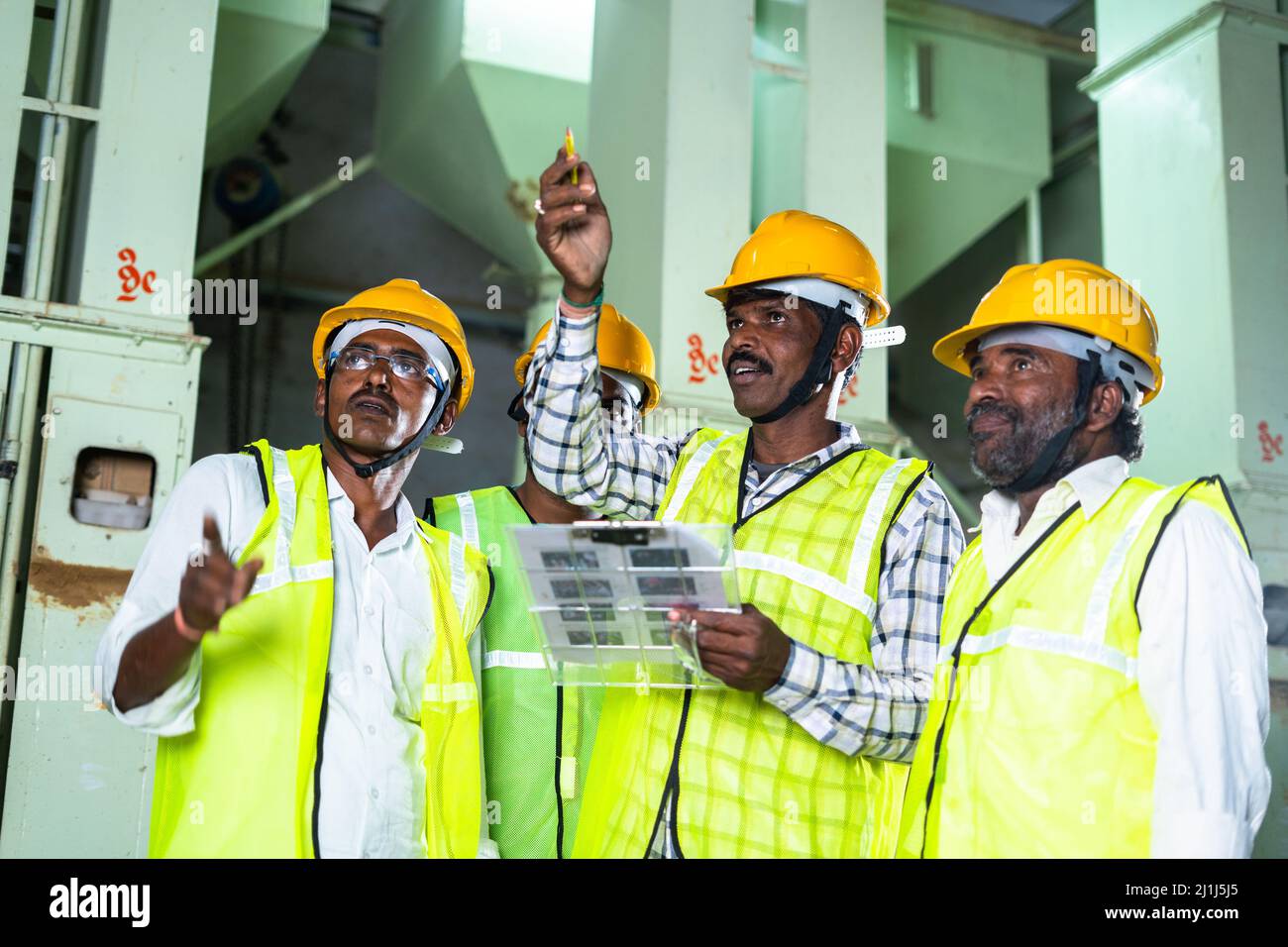 team of industrial workers discussing from clipboard about working ...
