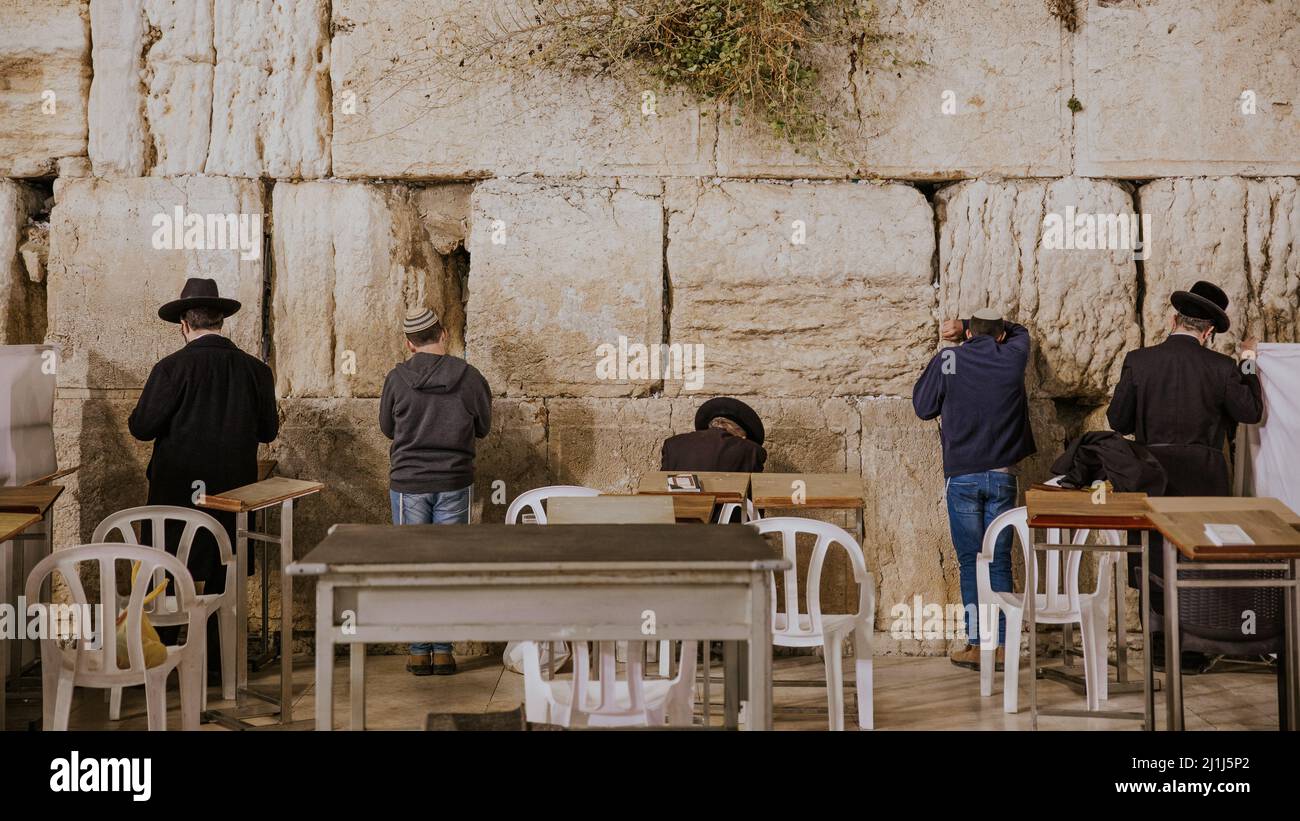 A back shot of visitors standing and praying by the Western Wall Shrine ...
