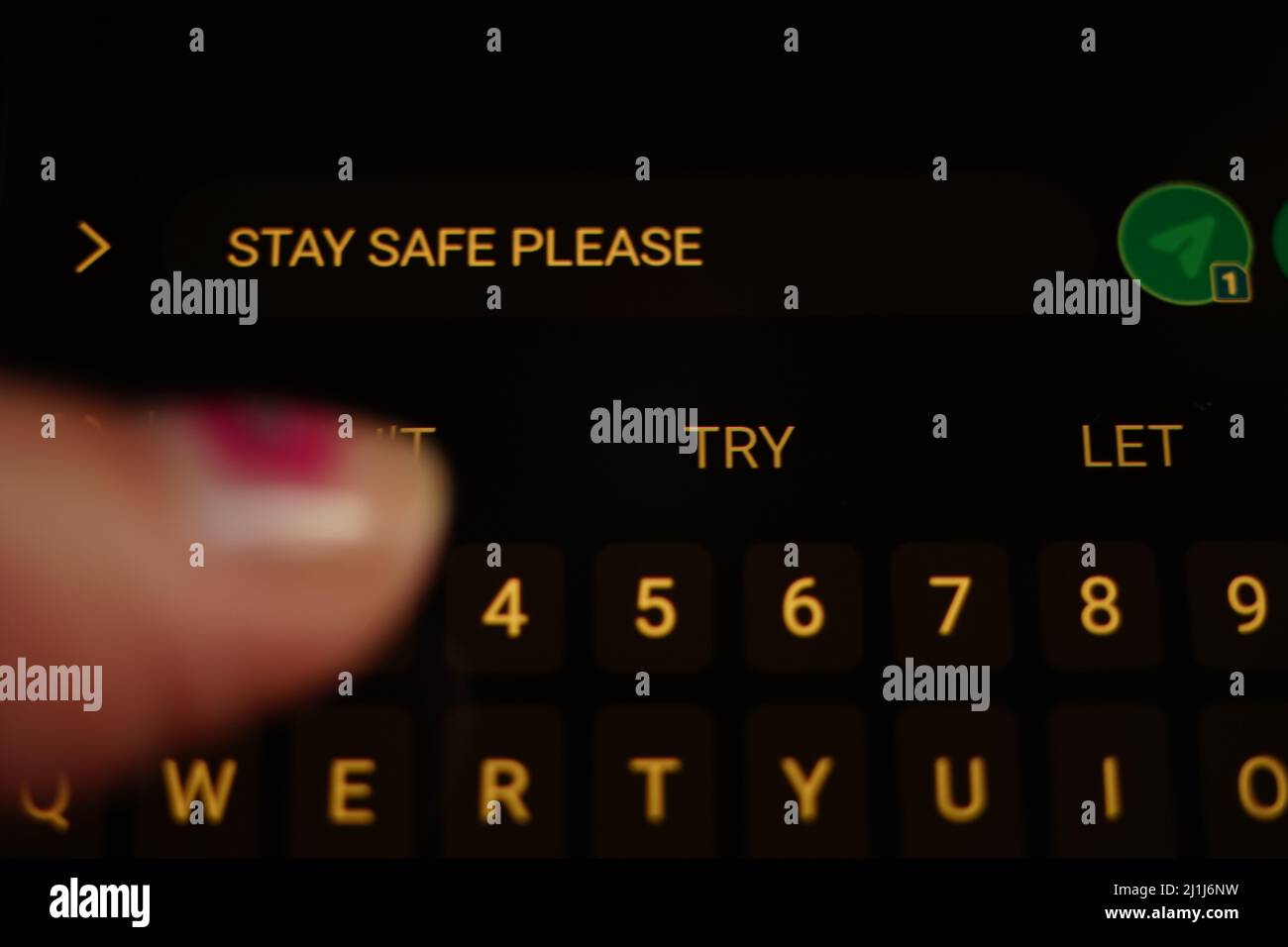 female finger typing STAY SAFE PLEASE message on black smartphone ...