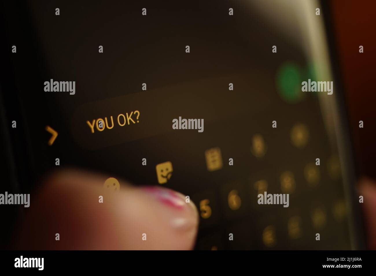 Young woman typing question YOU OK message on black smartphone screen ...