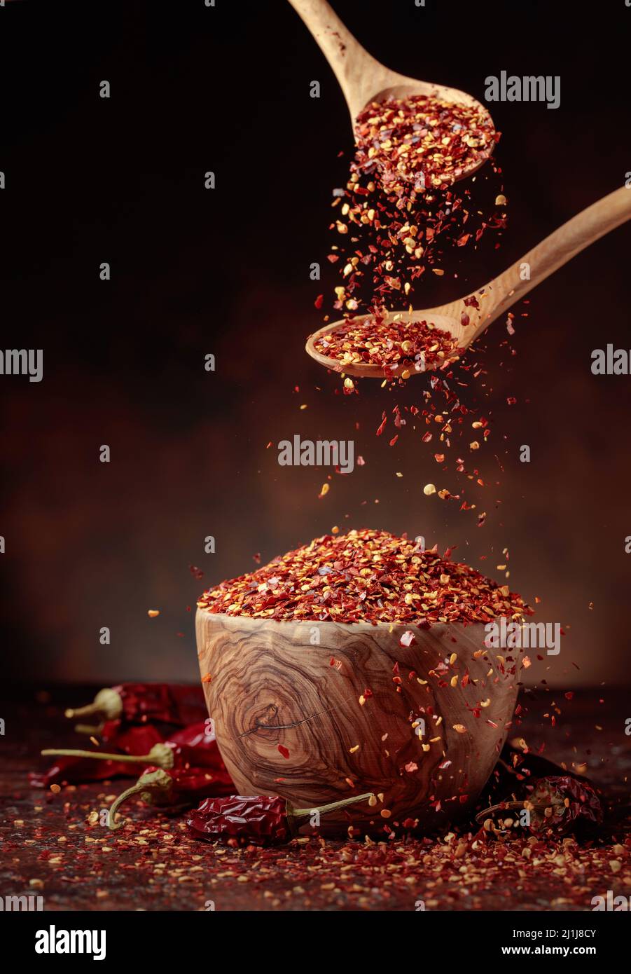 Chilli flakes are poured into a wooden dish. Chilli flakes and dried ...