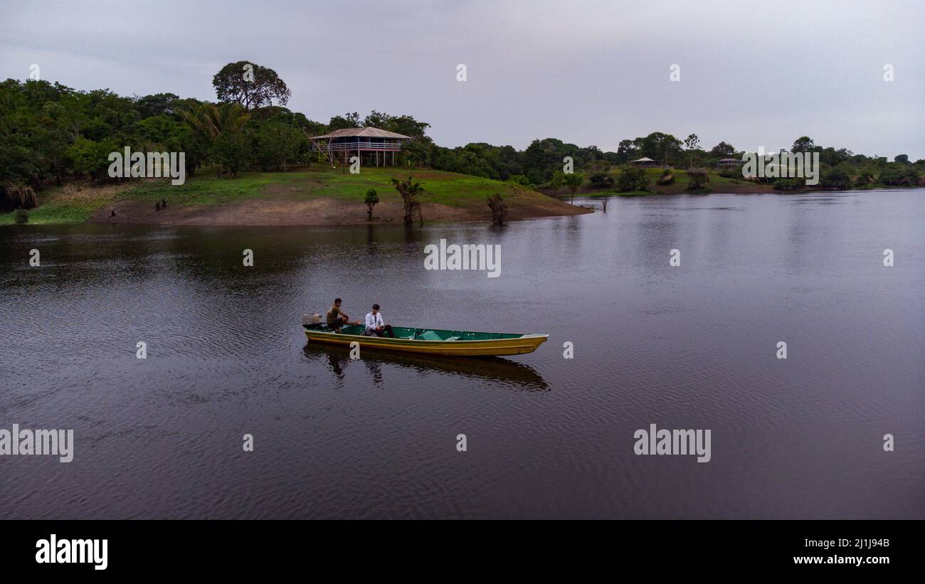 The people in a small boat crossing the Amazon river on a gloomy day ...
